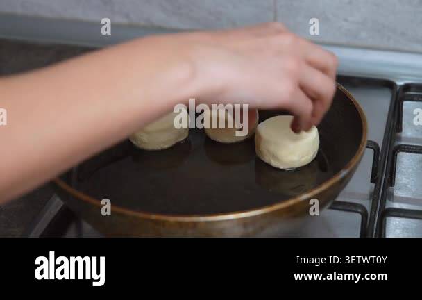 Close-up of a person's hands carefully placing small, round raw dough ...