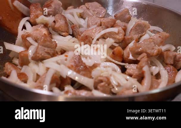 Close up view of succulent pork pieces and fresh sliced onions being ...