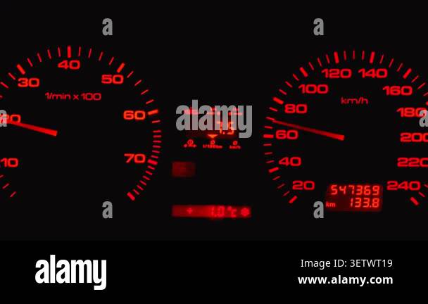 Luminous red car dashboard at night with the speedometer needle moving ...