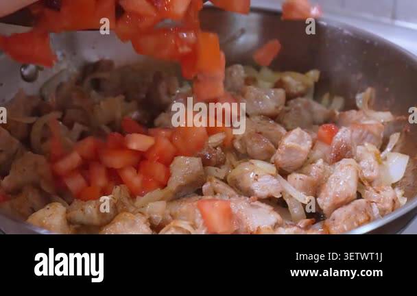 Professional chef preparing a delicious pork stew, adding fresh diced ...