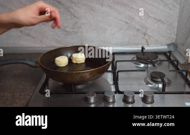 Female hands carefully placing raw syrniki, traditional cottage cheese ...