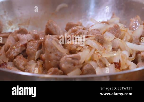 Close up view of succulent pork pieces and fresh sliced onions being ...