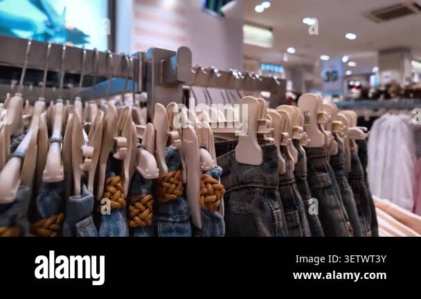 Close-up view of denim jeans hanging on a metal rack in a modern retail ...