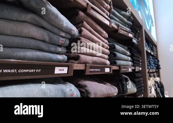 Shelves stacked high with a variety of folded denim jeans in a retail ...