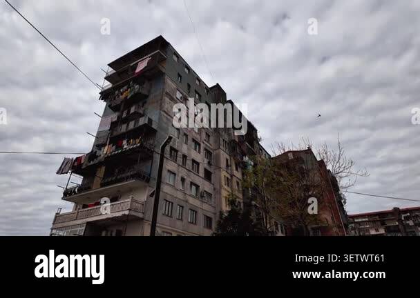 A dirty concrete apartment building under a dramatic cloudy sky ...