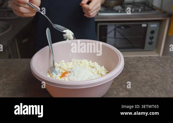 Close-up shot of a person's hands adding flour with a spoon into a pink ...