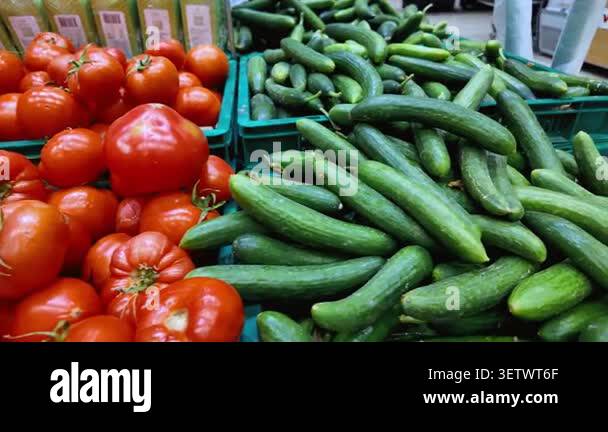 Fresh red tomatoes and green cucumbers for sale in green plastic crates ...