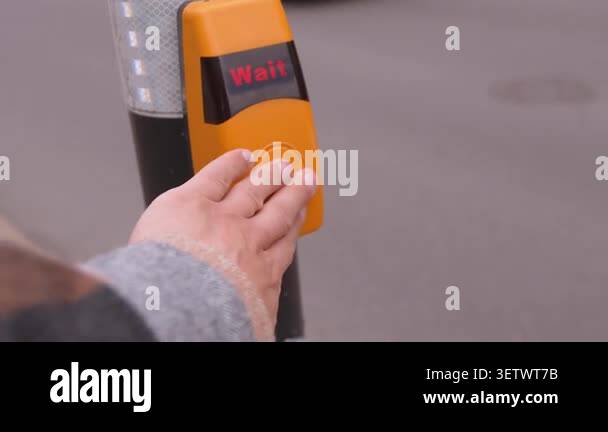 Close-up of a person's hand pressing a yellow pedestrian crossing ...