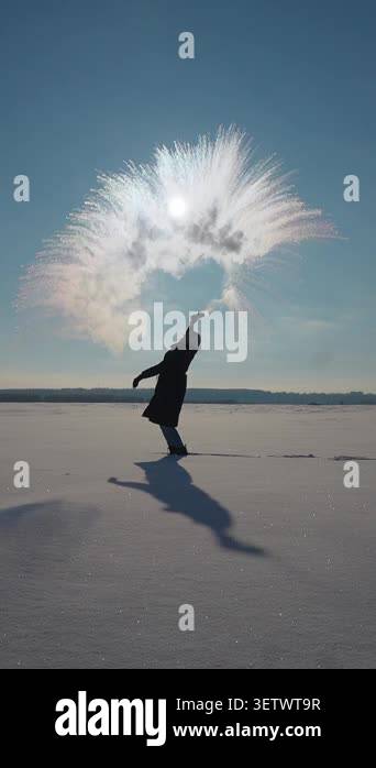 Silhouette of a woman standing in a snowy landscape throwing hot water ...