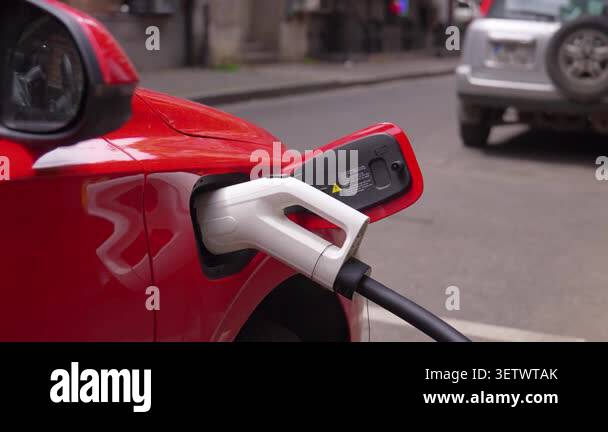 Close-up view of a modern red electric vehicle connected to a charging ...