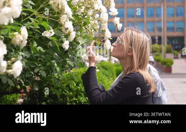 Side view of a beautiful blonde woman in sunglasses smelling fragrant ...