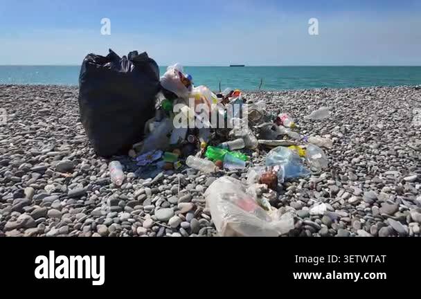 Plastic waste and other rubbish piled up on a pebble beach ...