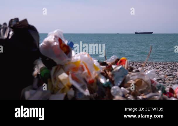 Plastic waste and other rubbish piled up on a pebble beach ...