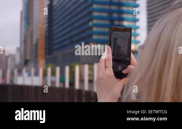 Close-up view from behind of a blonde woman holding a smartphone and ...