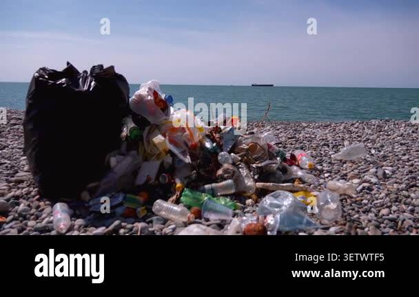 Plastic waste and other rubbish piled up on a pebble beach ...