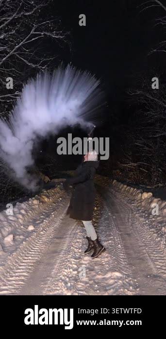 Young woman throwing boiling water from a thermos into the freezing air ...