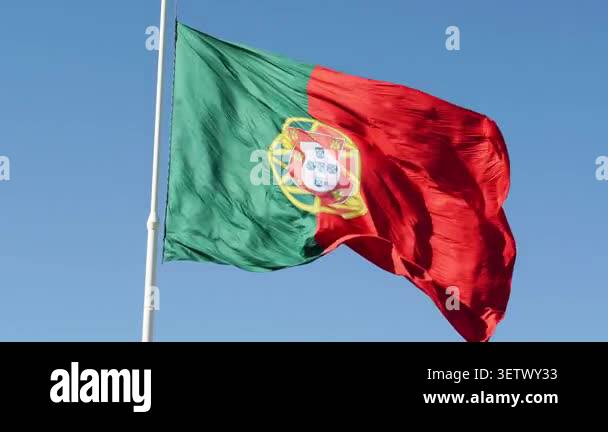 The big flag of Portugal waving intensely in the wind on a white ...