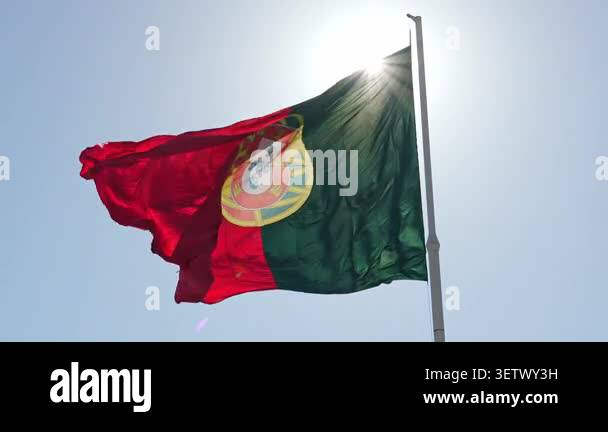 The big national flag of Portugal fluttering on a tall flagpole with ...