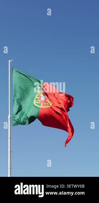 Big flag of Portugal fluttering in the wind on a white flagpole ...