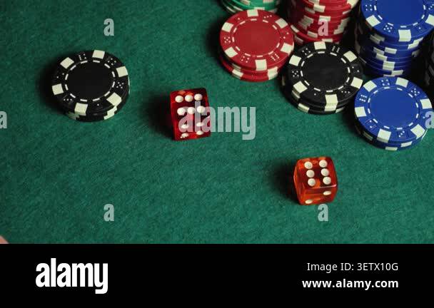A hand moves to place poker chips and dice on a green felt table ...