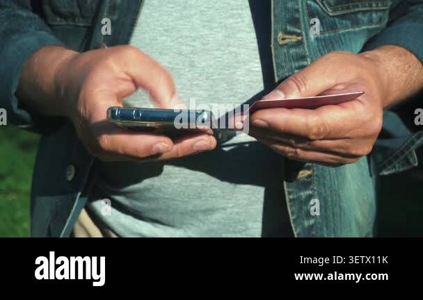 Man holding a smartphone in one hand and a credit card in the other ...