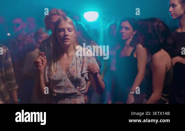 A woman dances joyfully at a vibrant party, where the camera captures ...