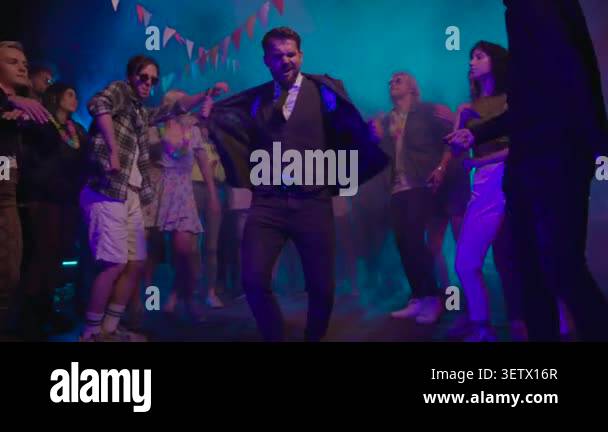 A man in a sharp suit showcases his dance moves at a lively party ...