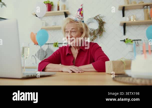 An elderly woman enjoys a virtual birthday celebration with beautiful ...