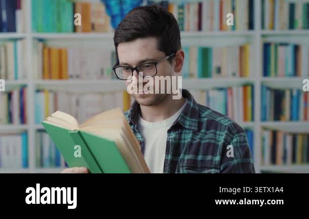 In a cozy library, a man with glasses immerses himself in a green book ...