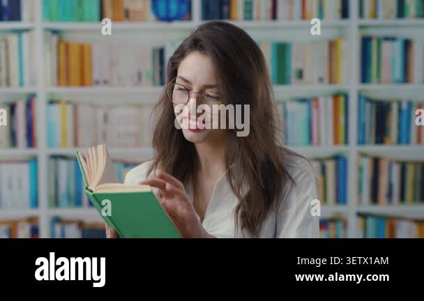 A woman with glasses is deeply engrossed in a book in a tranquil ...