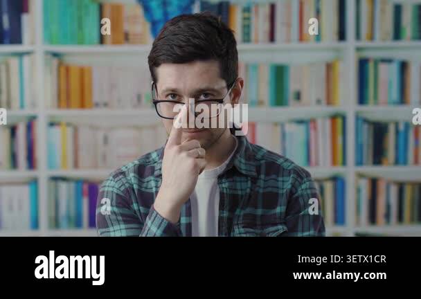 The video shows a thoughtful man in glasses in a serene library ...