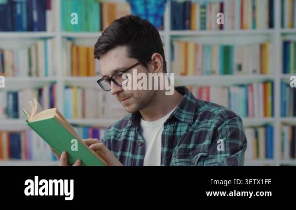 A man who is wearing a pair of glasses is intently reading a book while ...