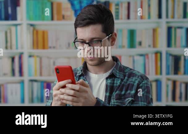 A man, who is wearing glasses, is currently using a cell phone while ...