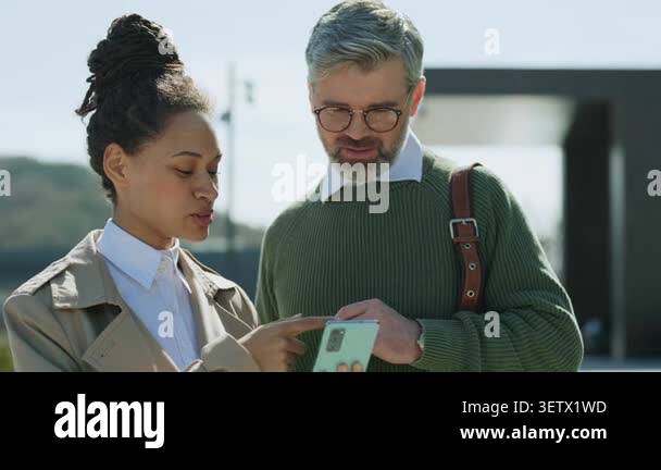 A man and woman closely examine a cell phone, sharing smiles and ...