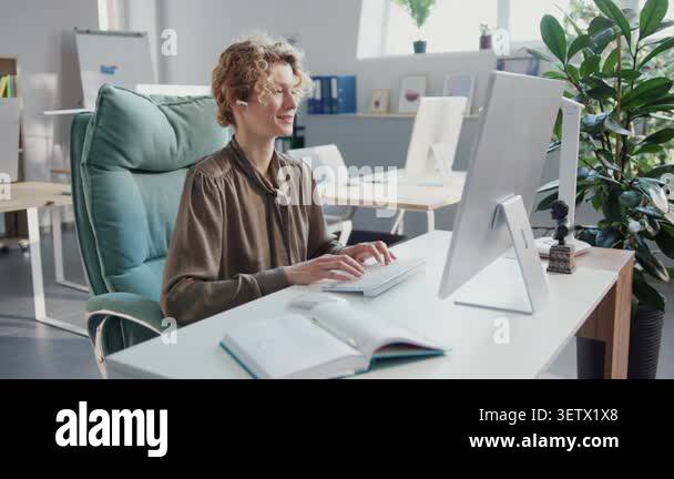 Beautiful Caucasian businesswoman with curly hair working with computer ...
