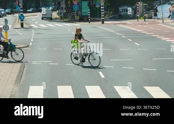 Amsterdam Cyclist Riding Across Sunlit City Intersection. High quality ...