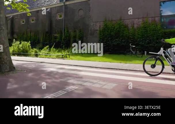 Amsterdam Cyclist Riding Past Brick Buildings On Shaded Street. High ...