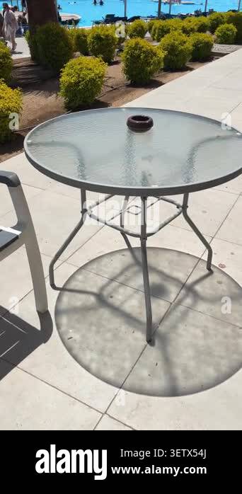 Glass patio table with an ashtray overlooking a tropical on June 20 ...