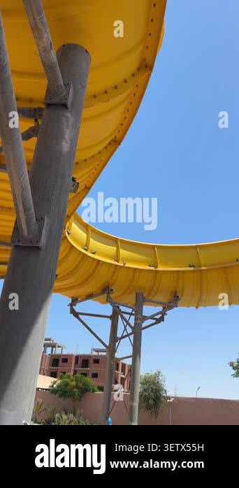 Low angle view of a yellow waterslide structure against a clear blue on ...