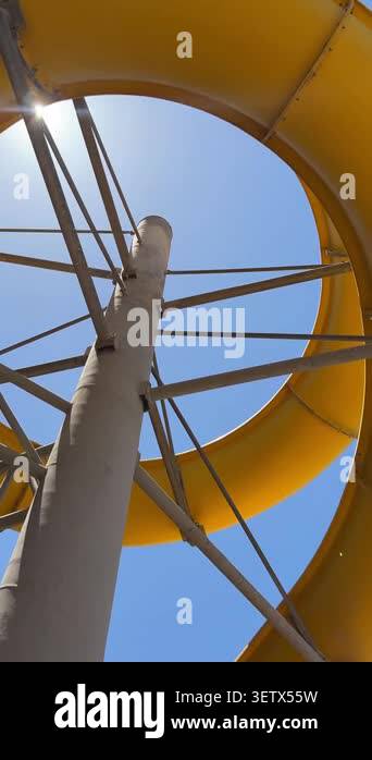 Low angle view of vibrant yellow water slide tubes at an outdoor park ...