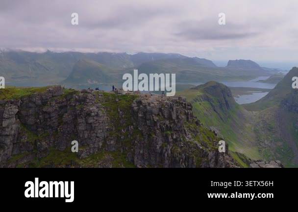 Aerial view of hikers exploring towering rocky cliffs and green ...