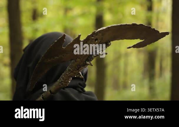 Weapon detail, Weapon closeup, Forest ambiance. Hooded person clutching ...