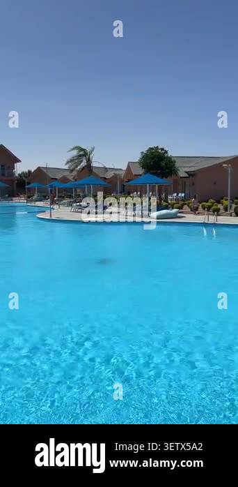 Sunlit luxury swimming pool with vibrant blue umbrellas on June 20 ...