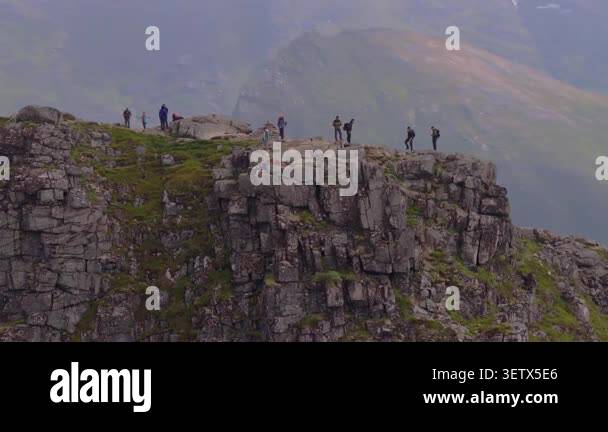Group of tourists hiking on dramatic rocky mountain peak in Lofoten ...