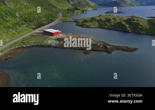Aerial view of a red fish farm facility on a rocky peninsula in Lofoten ...