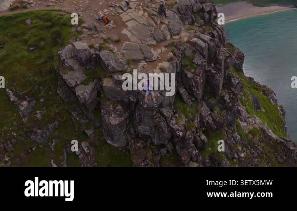 Aerial view of rock climber ascending vertical cliff with turquoise ...