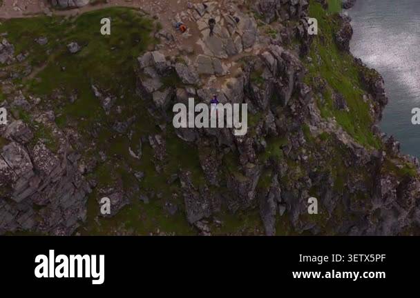 Aerial footage of hikers exploring dramatic moss-covered rocky cliffs ...