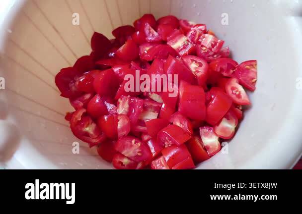 High angle studio view of juicy ripe red tomatoes diced in small pieces ...