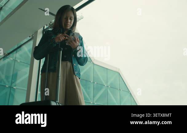 A woman with a suitcase talks on the phone while waiting for her flight ...