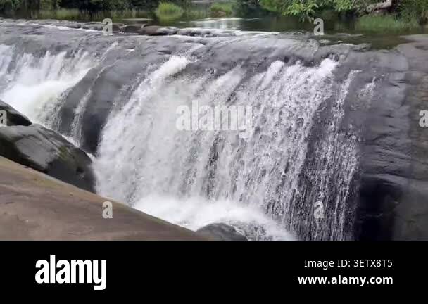 Scenic footage of beautiful waterfall rushing over dark river rocks ...